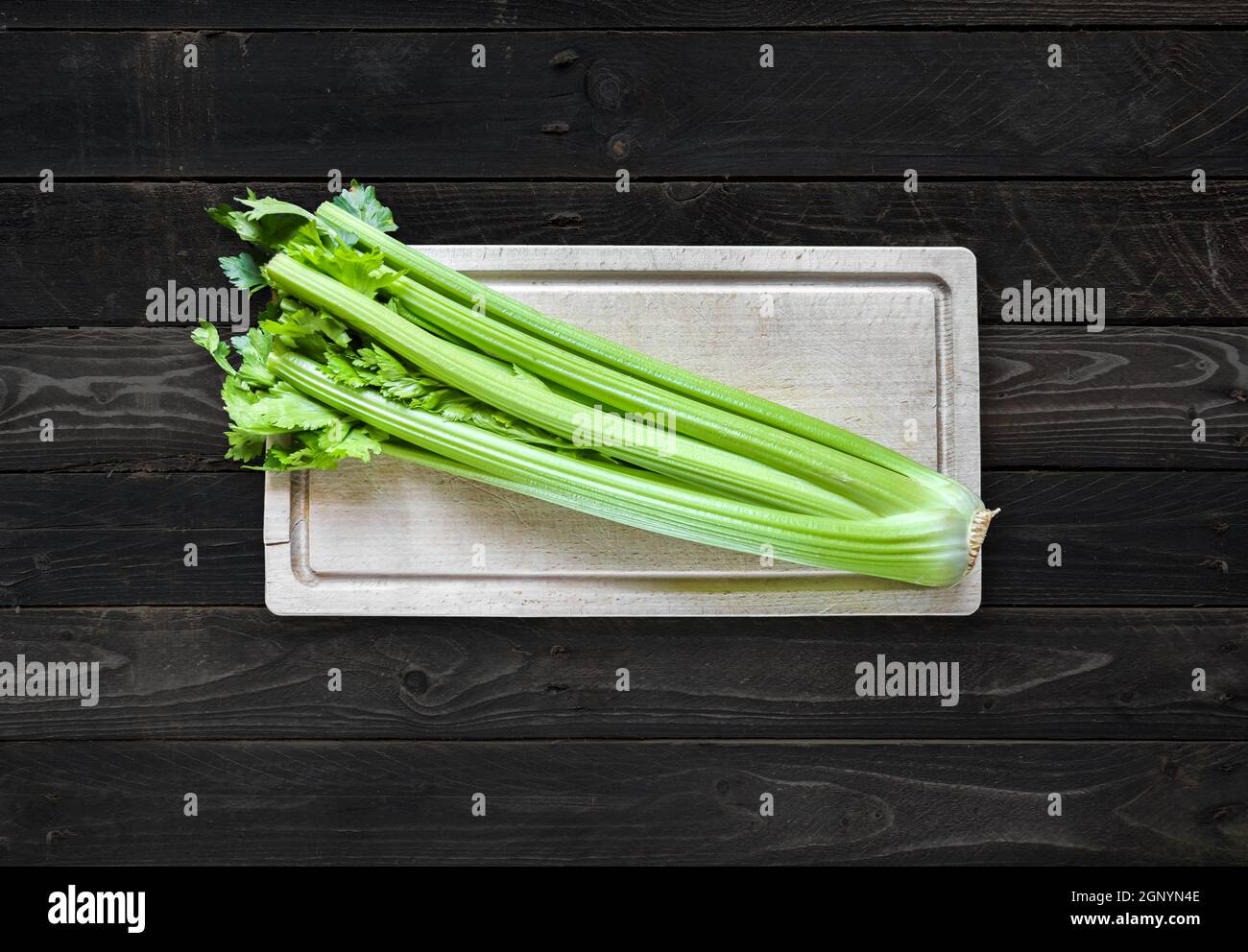 Celery branch bunch on black wood table background Stock Photo - Alamy