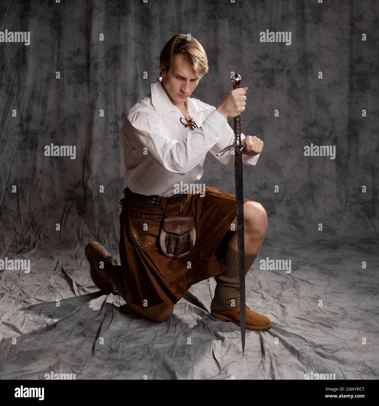 The Scottish knight knelt, took an oath, concept. A young man in a kilt ...