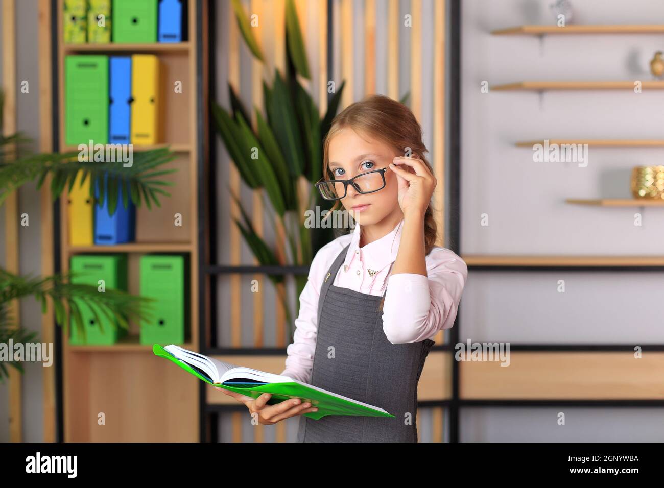 Portrait of a girl in a school uniform with a book in her hands. The ...
