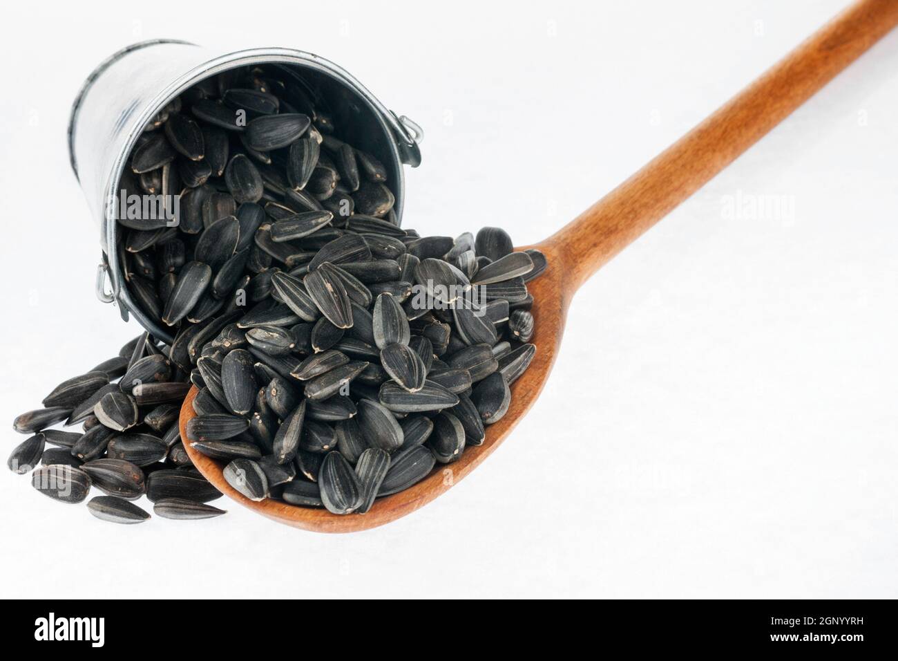 Bucket of sunflower seeds crumbles in the a wooden spoon, on a white ...