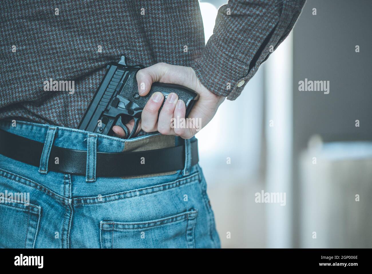 Undercover police agent is holding a black hidden weapon in his hand ...