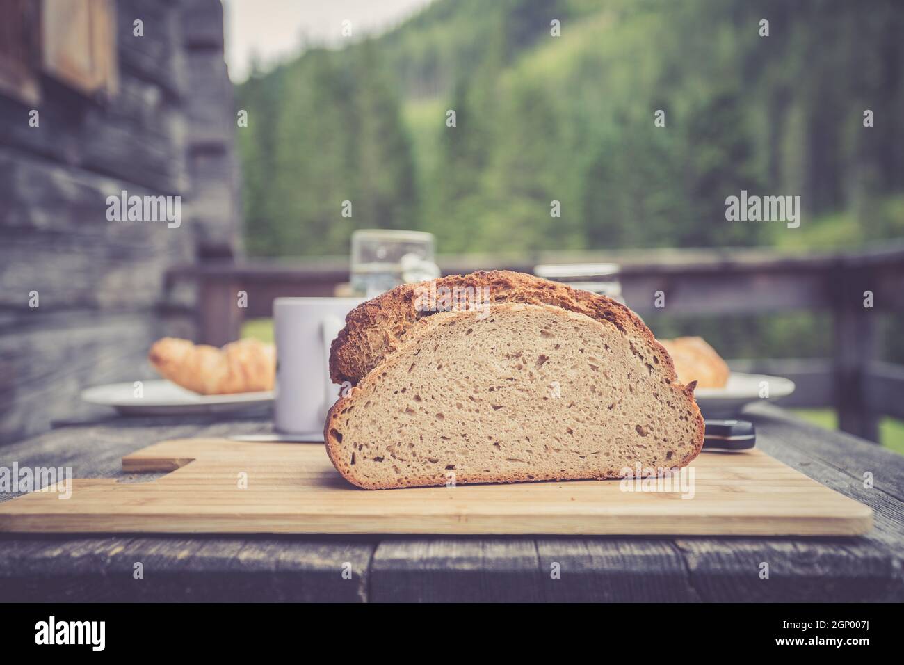 Fresh dark crisp bread for breakfast on an alpine hut. Wooden cutting ...