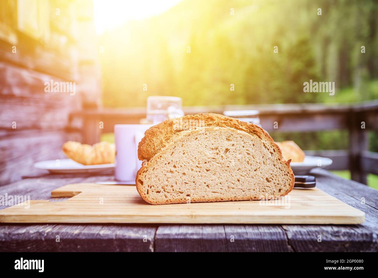 Fresh dark crisp bread for breakfast on an alpine hut. Wooden cutting ...