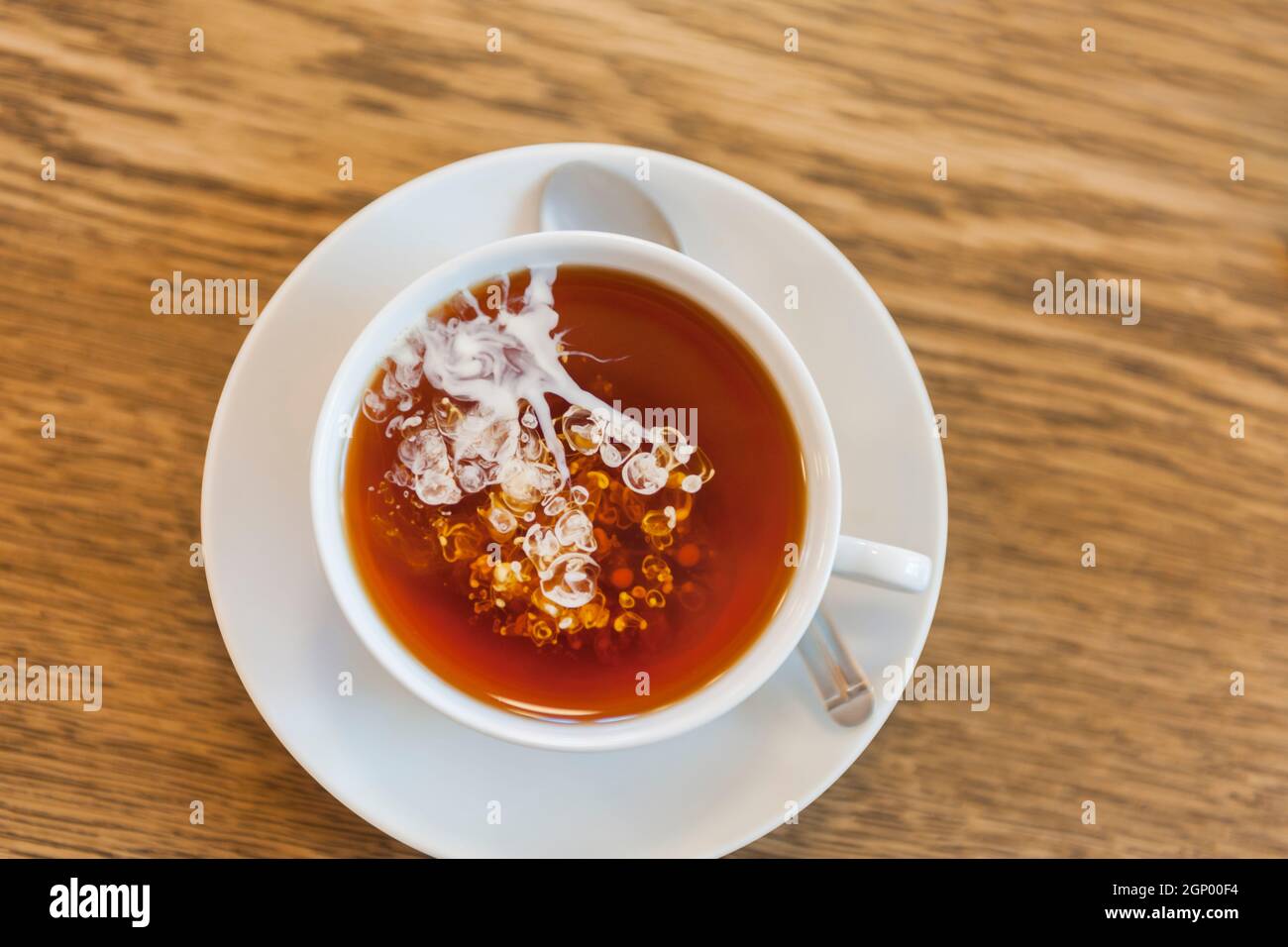 Top View Closeup of a white cup of tea with freshly poured cream ...