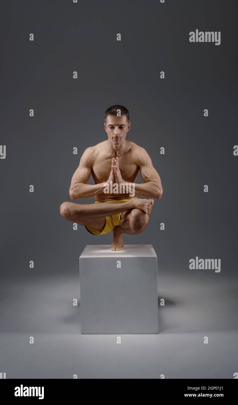 Male yoga keeps balanc on hands in difficult pose on the pedestal ...