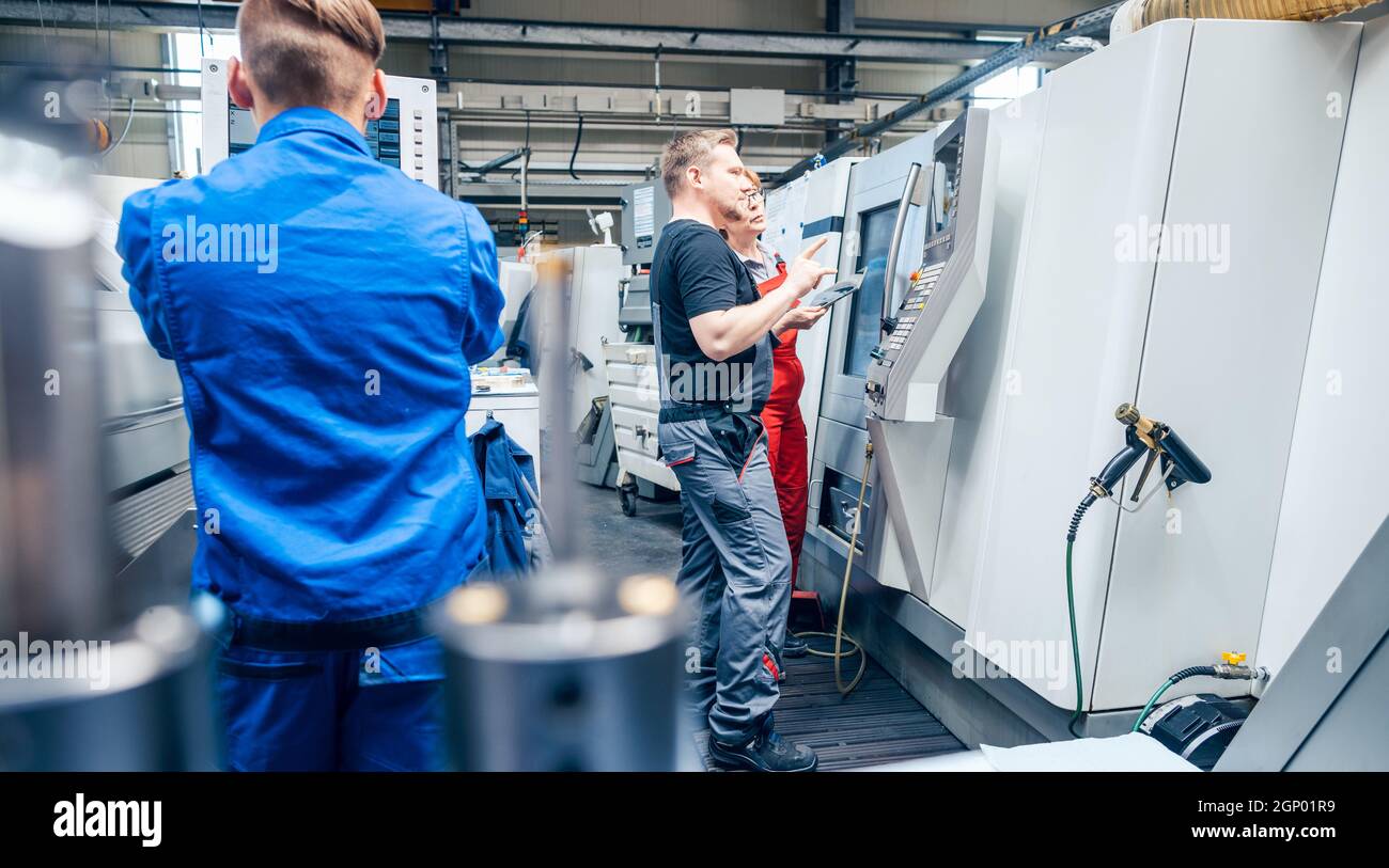 Factory floor with workers at cnc lathe machine Stock Photo - Alamy