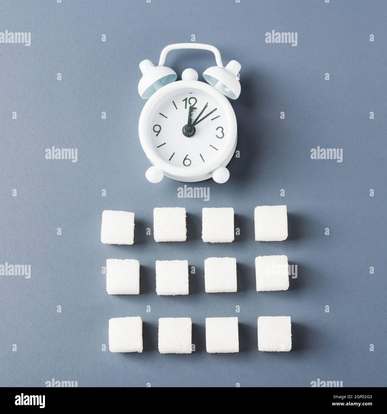 White sugar cube sweet food ingredient geometry pattern and alarm clock ...