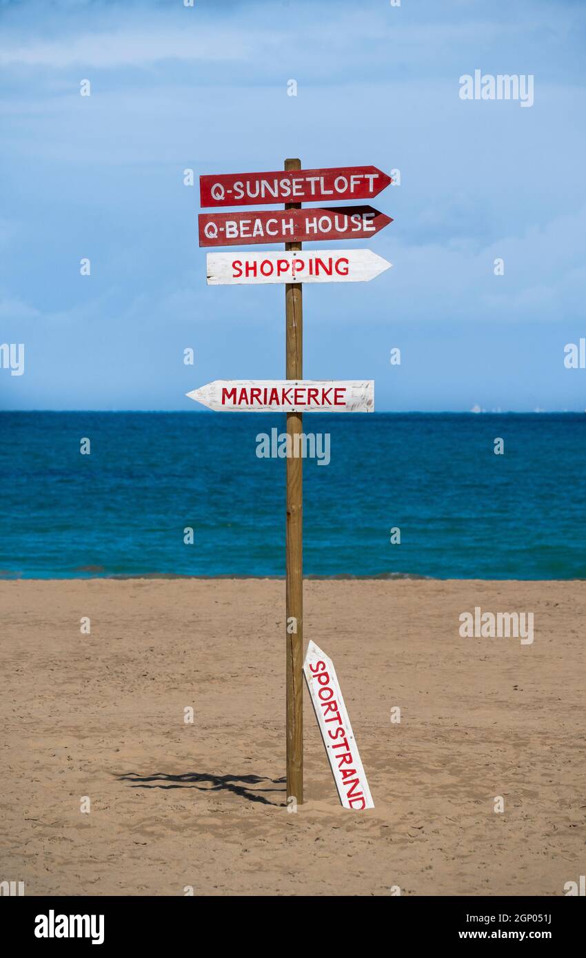 Beach sign showing the directions in front of the blue ocean in ...