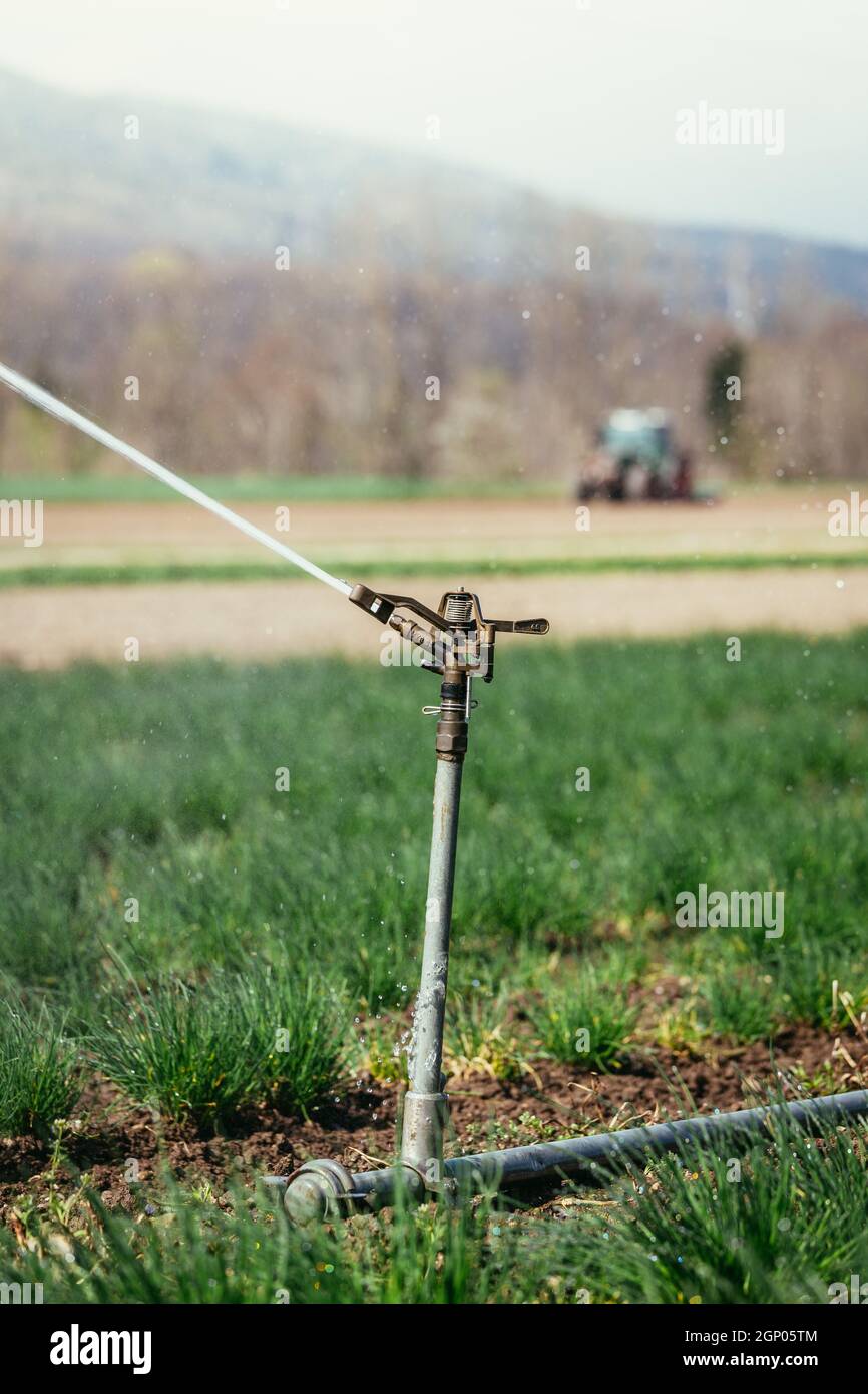 Irrigation plant on an agriculture field, tractor in the background ...