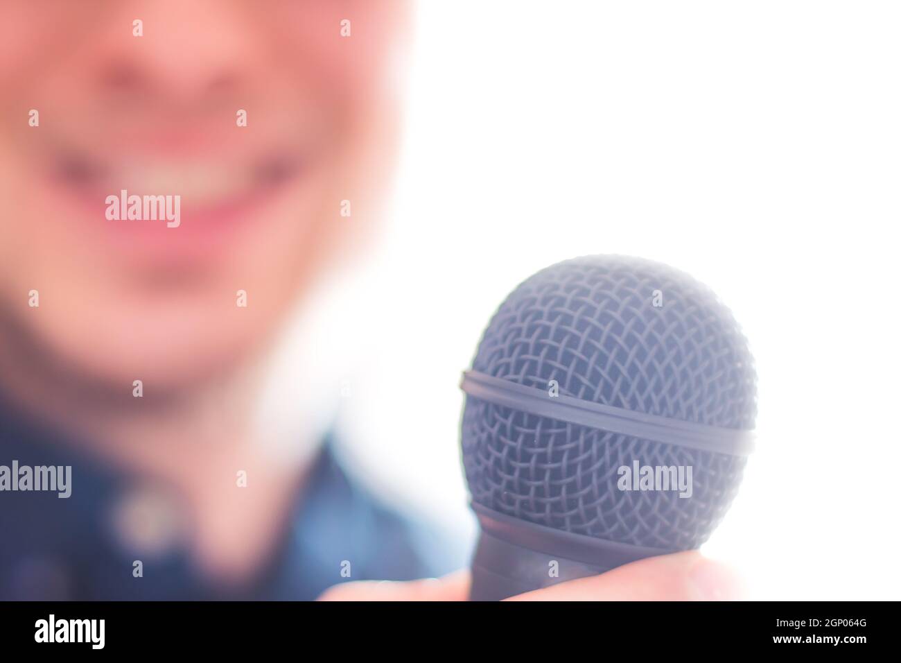 Young man holding a black microphone and speaking into it Stock Photo ...