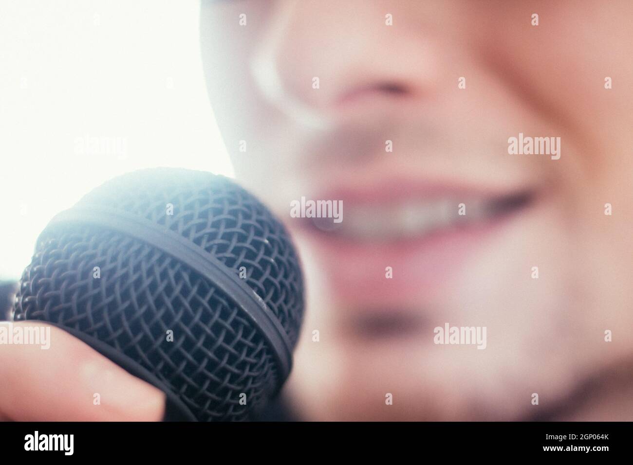Young man holding a black microphone and speaking into it Stock Photo ...