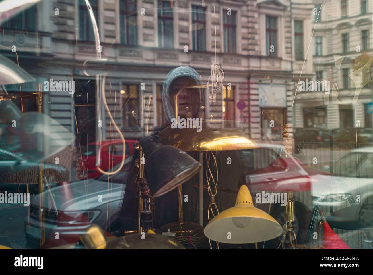 The reflection of a young man in a shop window with old lamps Stock ...