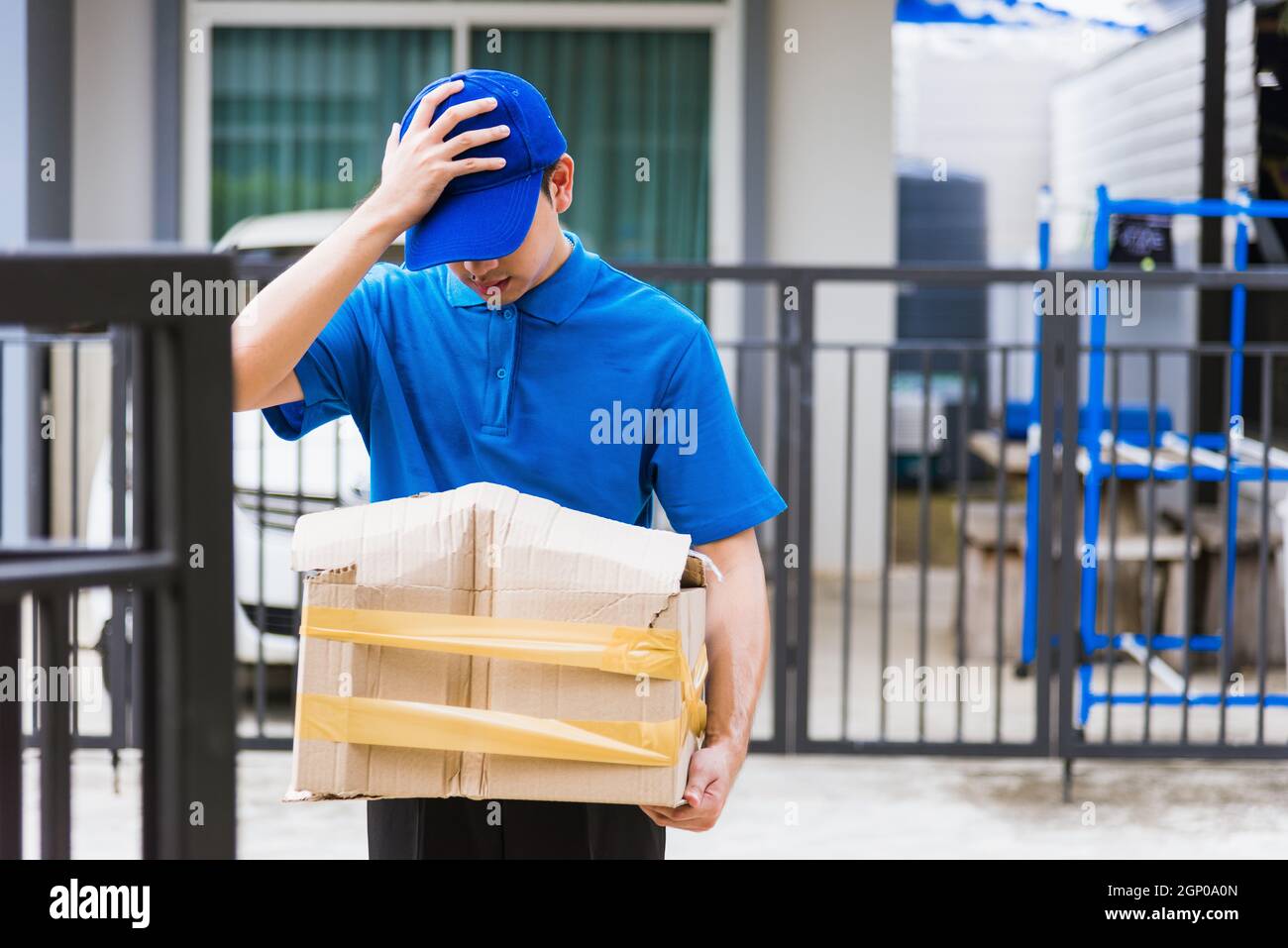 Asian young delivery man in blue uniform he emotional falling courier ...