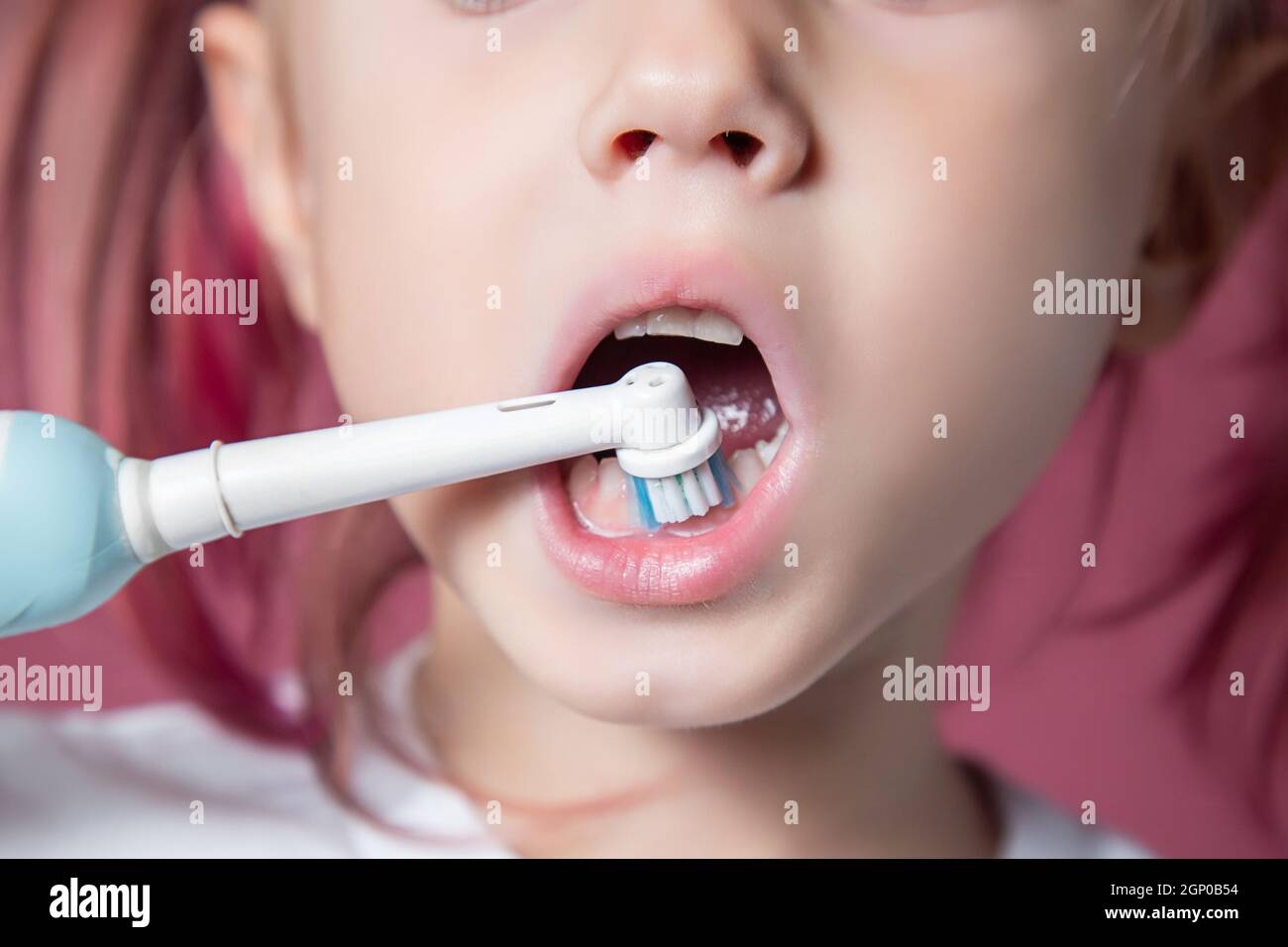 Smiling caucasian little girl cleaning his teeth with electric sonic ...
