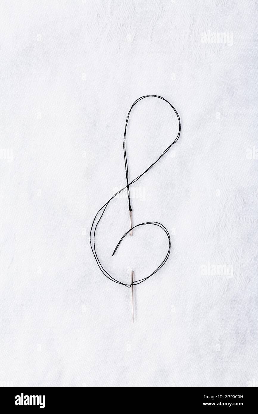 Macro of sewing needle in white fabric in violin key shape. Concept of ...