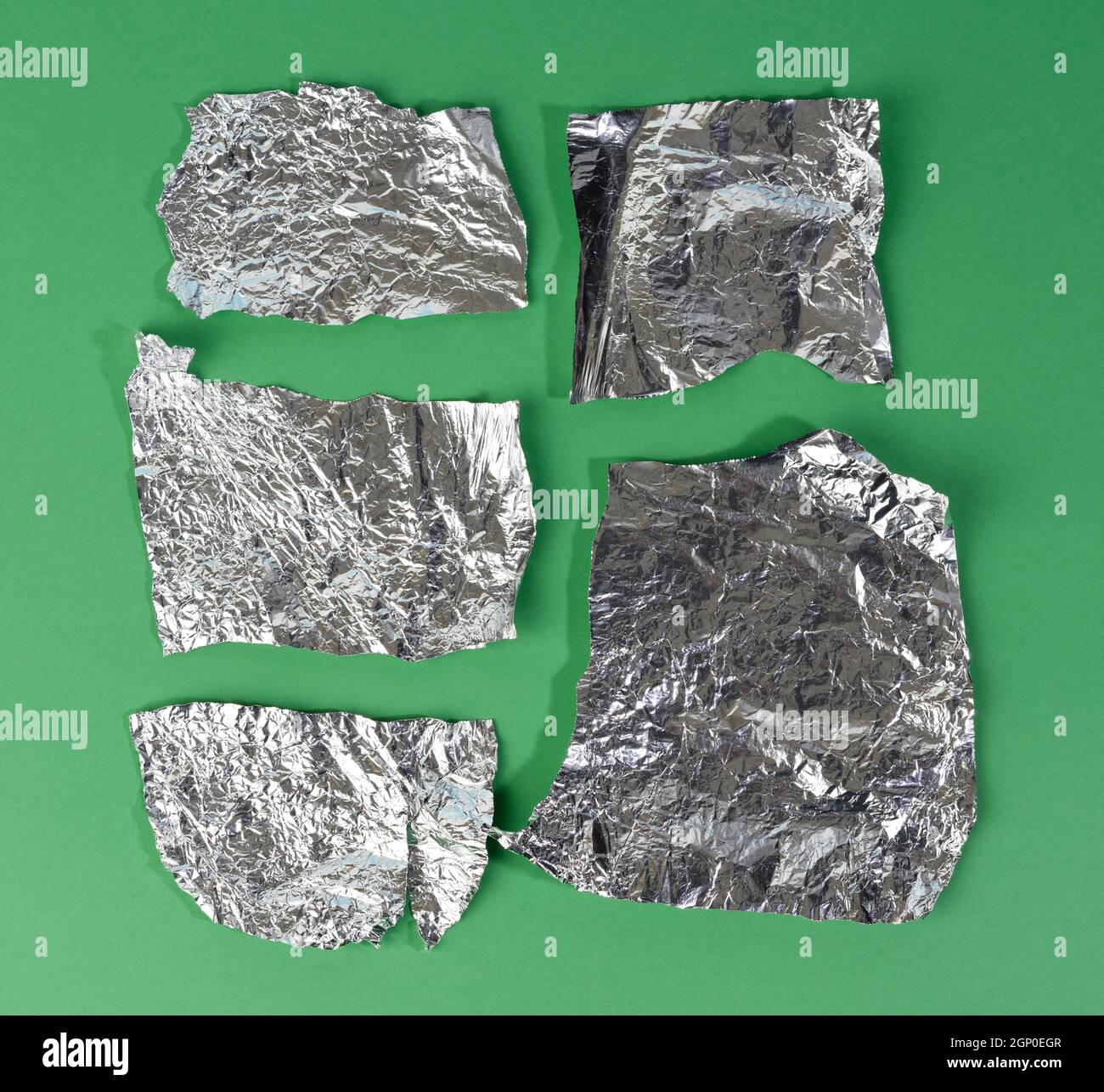 various pieces of foil on a green background, top view Stock Photo - Alamy