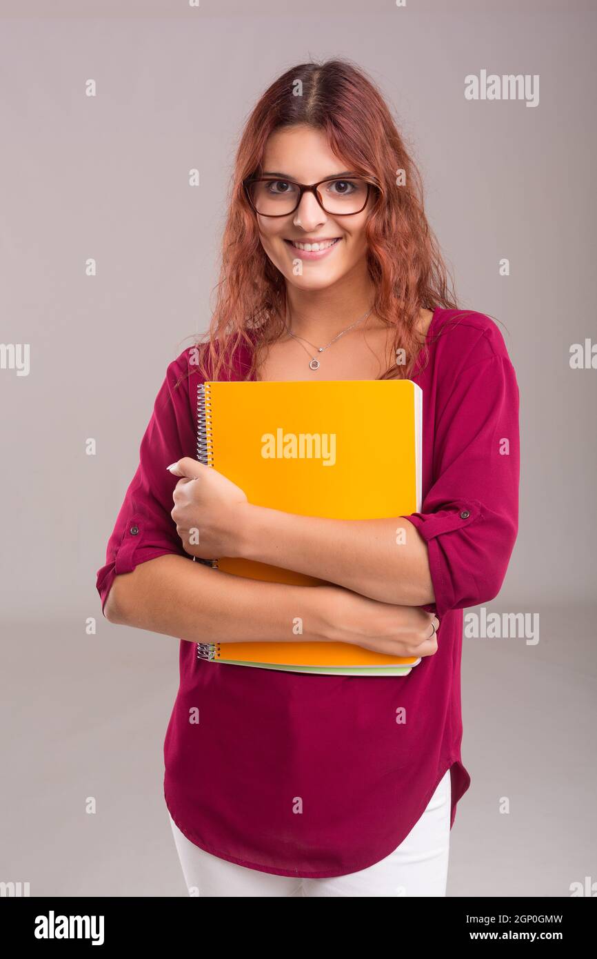 Studio shot of a young woman carrying some books Stock Photo - Alamy