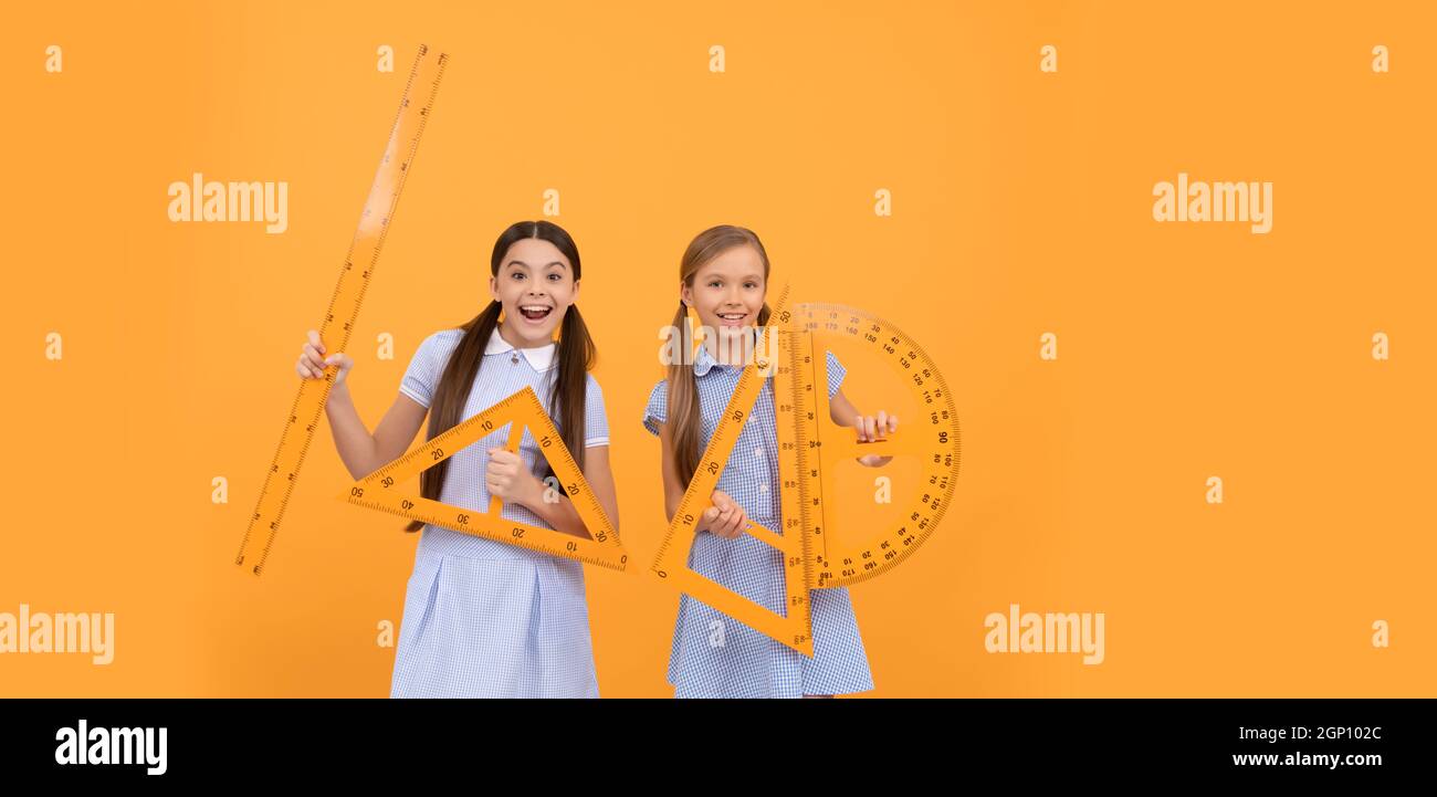 Happy teen girls hold geometric tools for geometry lesson orange ...