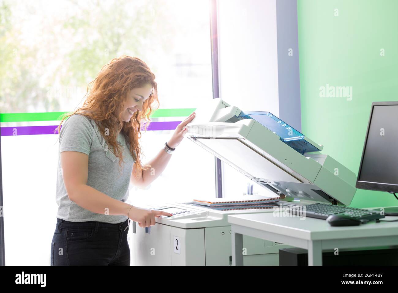 A young student at a copy center taking some copies for her final exams ...