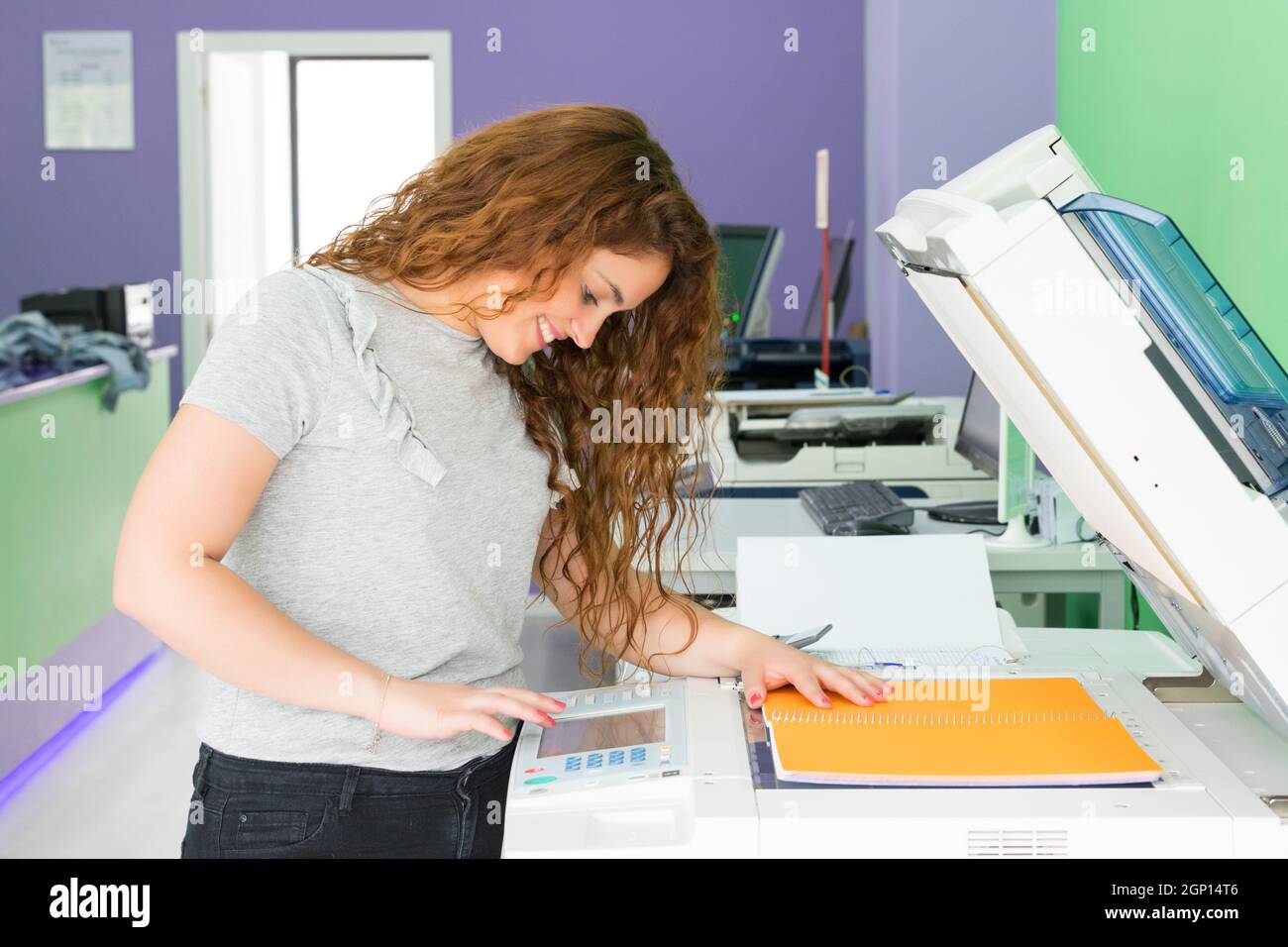 A young student at a copy center taking some copies for her final exams ...
