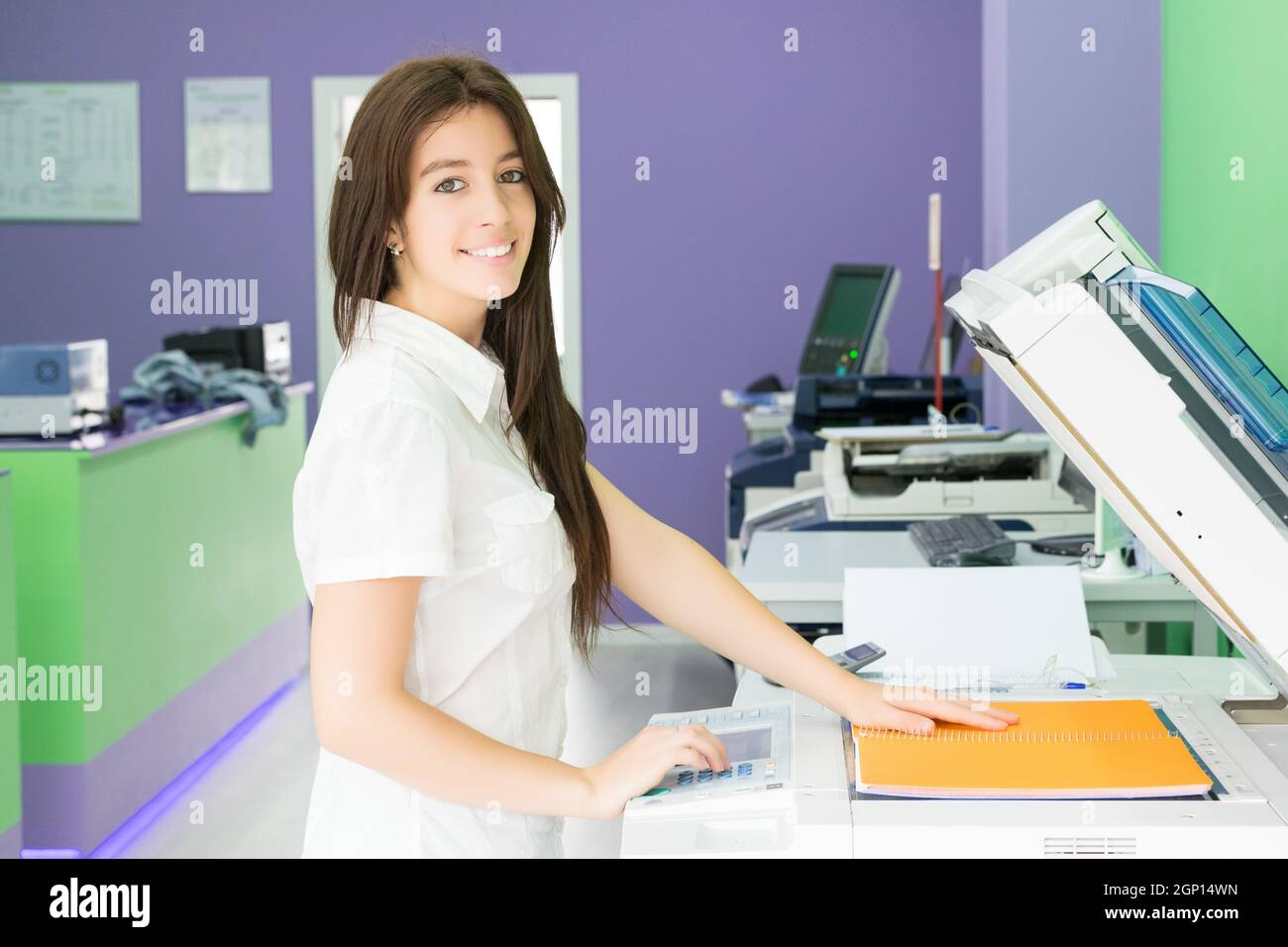 A young student at a copy center taking some copies for her final exams ...