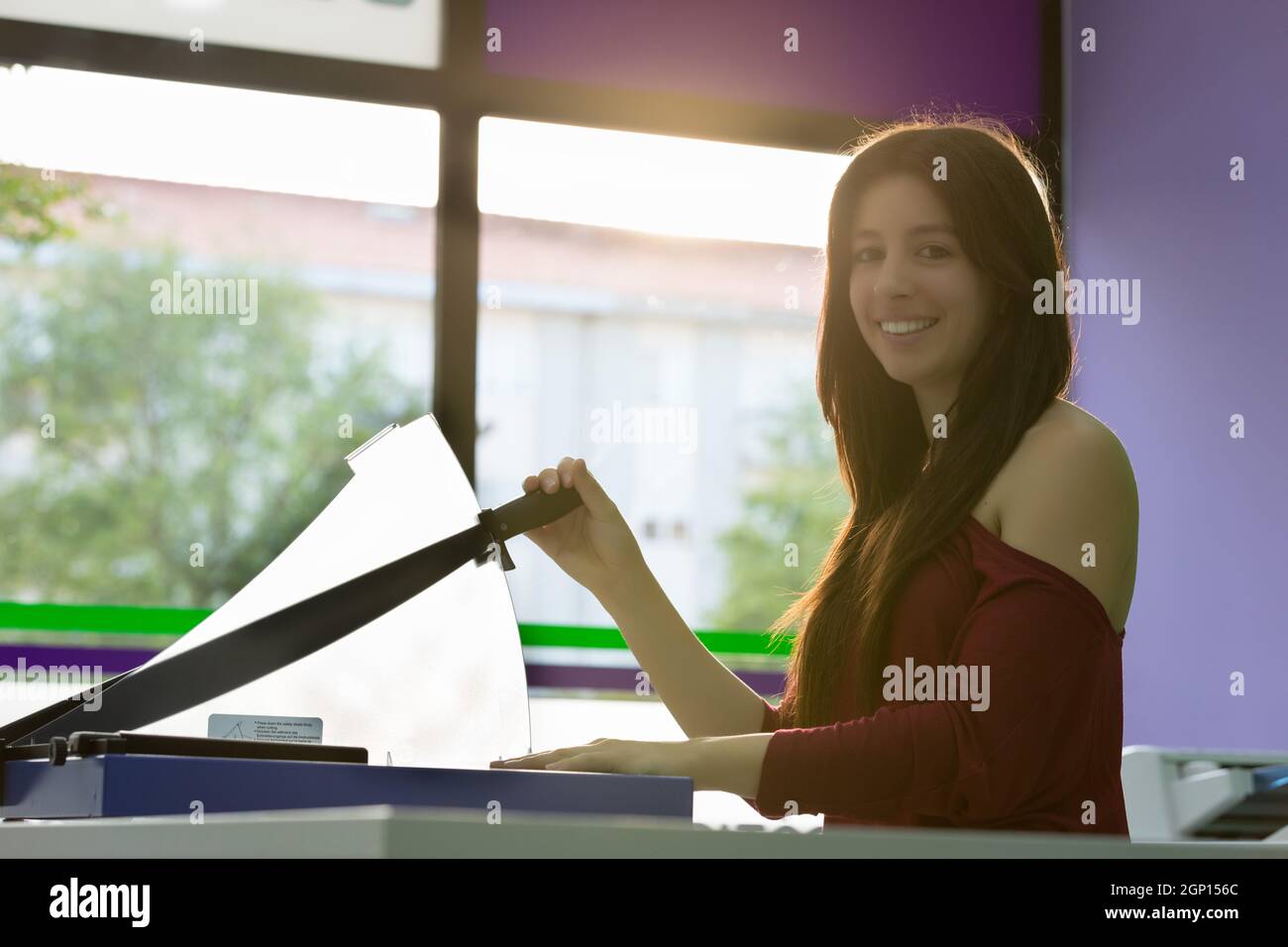 A young student at a copy center taking some copies for her final exams ...