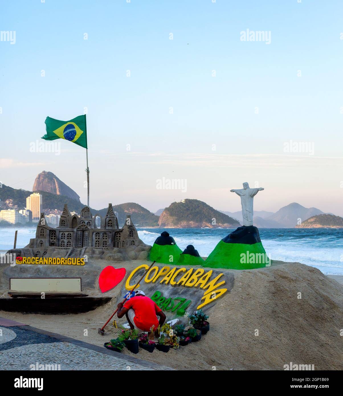 A traditional sand castle sculpture in the Christ of Rio and a flag is ...