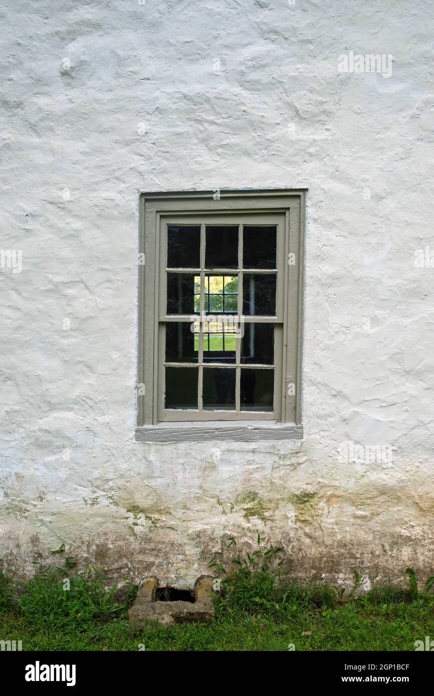 Vertical image of a whitewashed stone exterior of a Colonial American ...