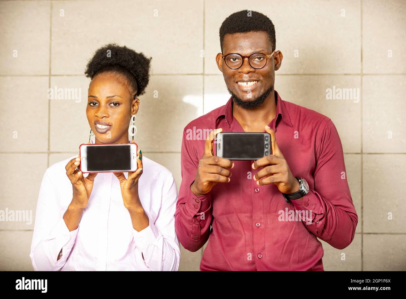 Two students stand together and hold their phones in their hands ...