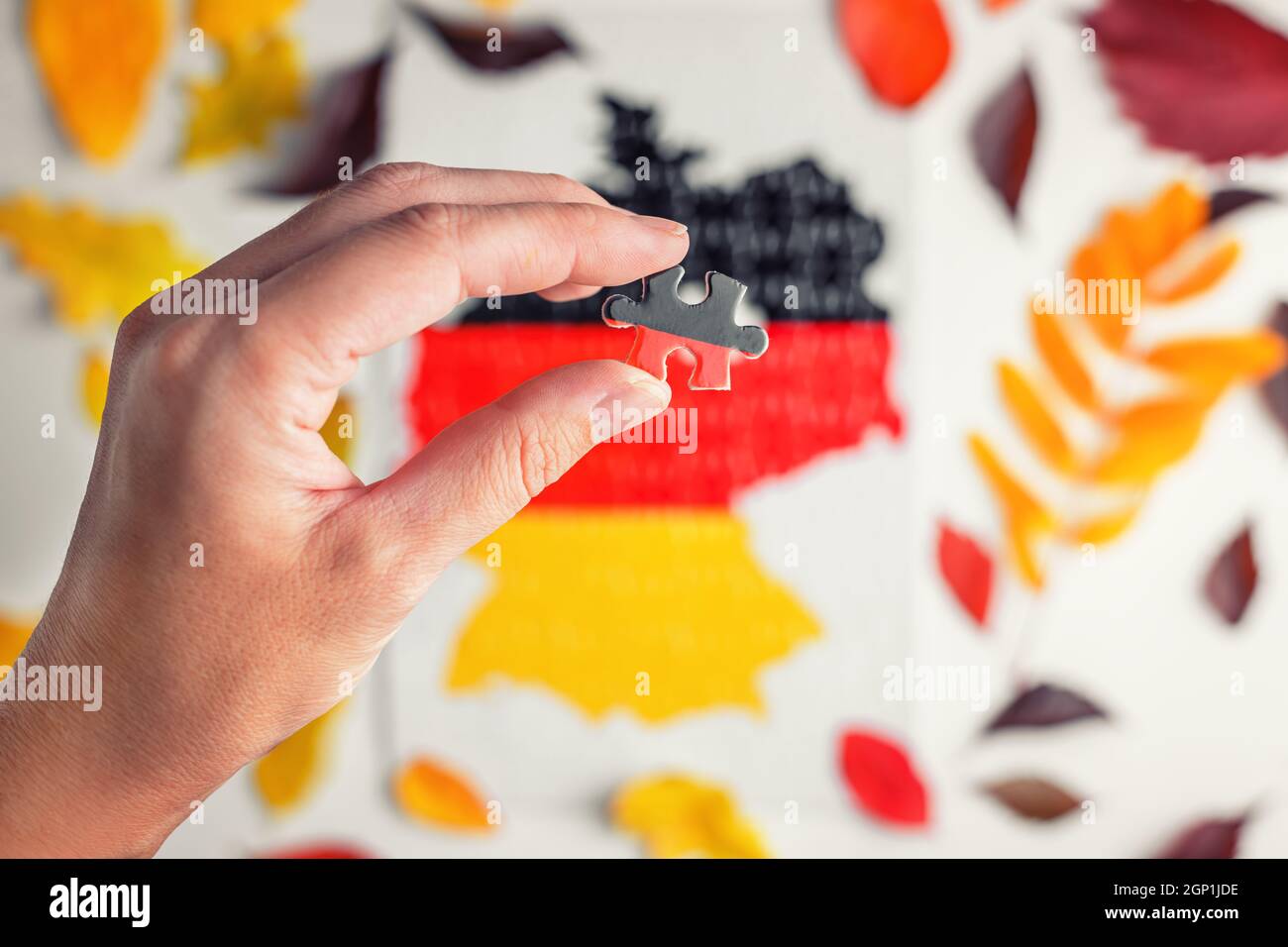 hand holds a piece of puzzle in the form of outlines of Germany in the ...
