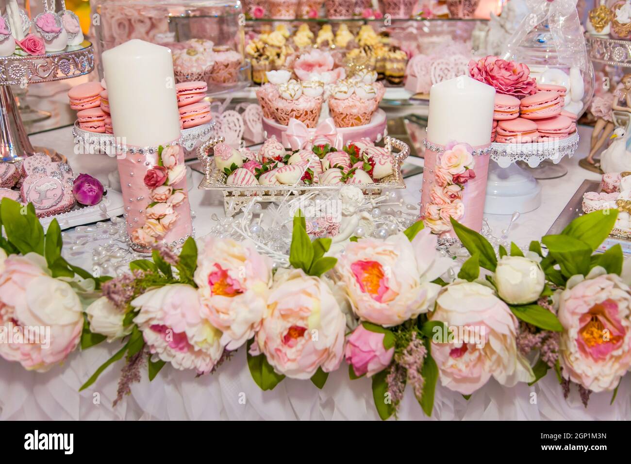 Delicious desserts at the wedding candy bar in the buffet area: decorated candles, rosebuds ...