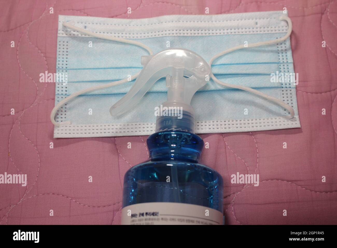 blue color cloth face mask with hand sanitizer bottle isolated on pink ...