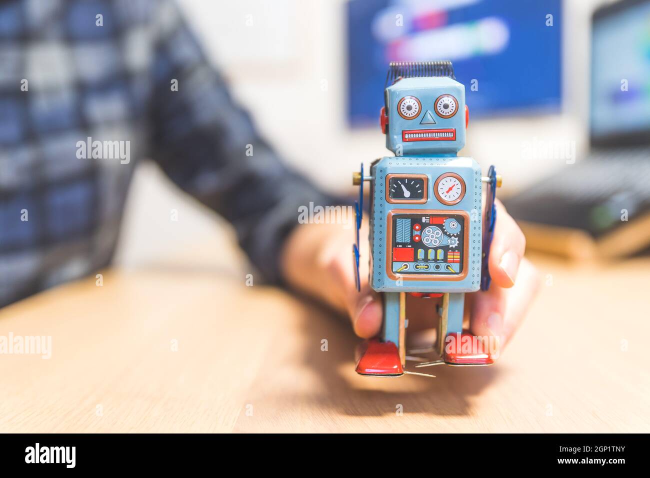 Toy robot on a desktop, man working on the computer in the background ...
