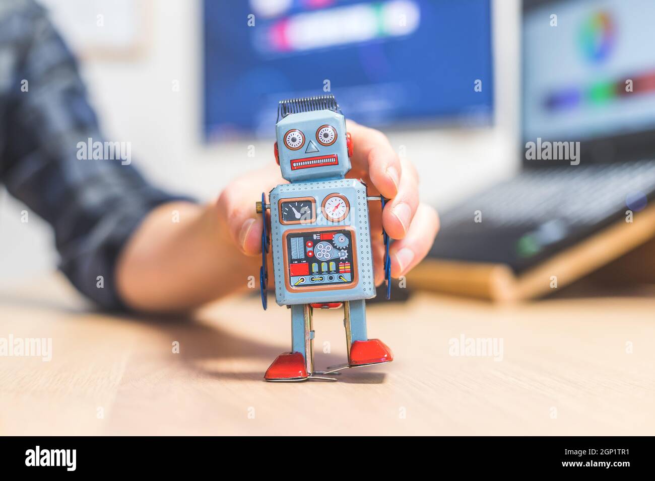 Toy robot on a desktop, man working on the computer in the background ...