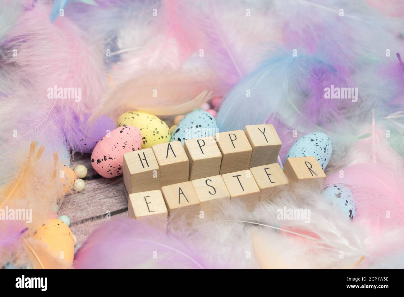 Happy Easter written with wooden cubes surrounded with beautiful pastel ...