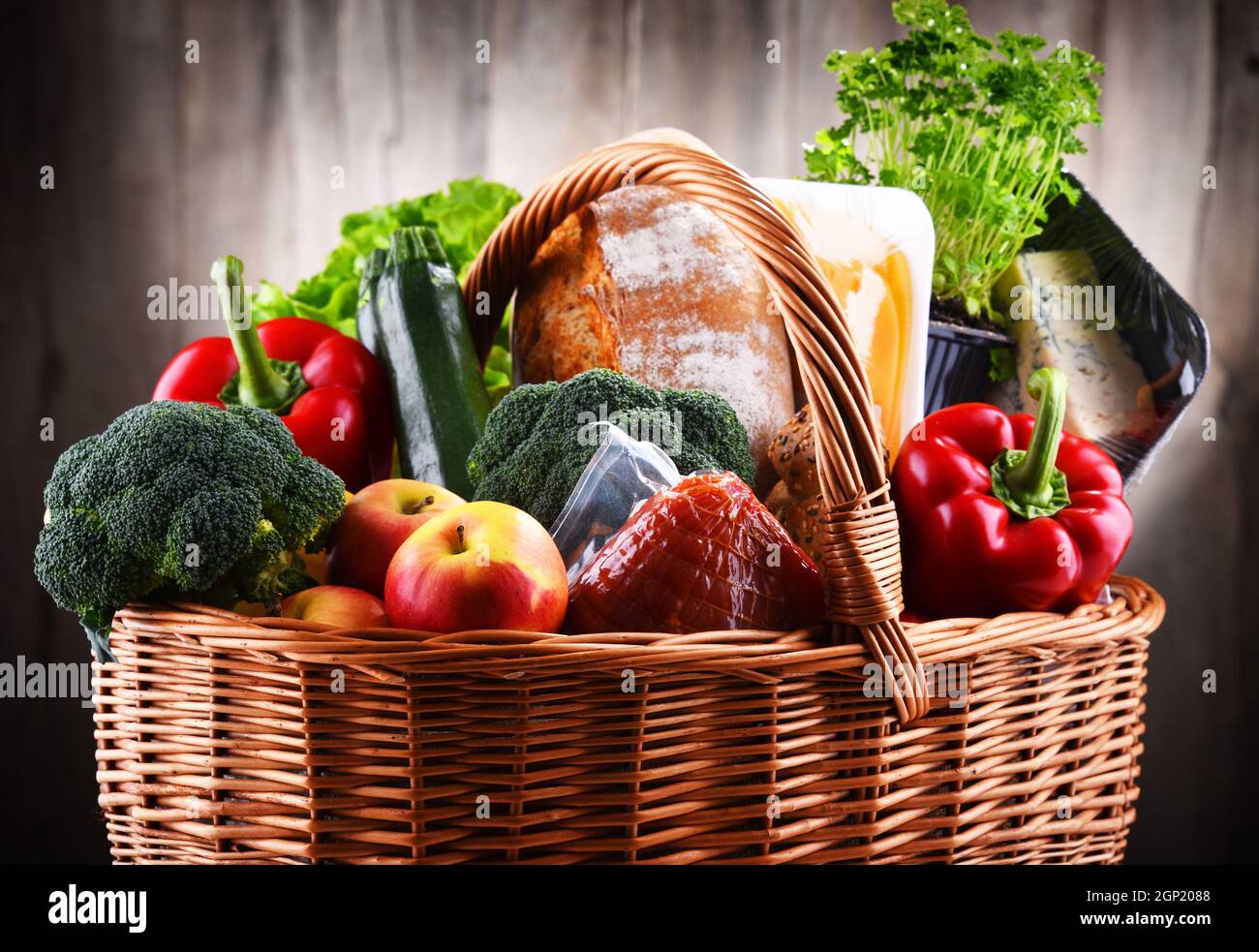 Wicker basket with assorted grocery products including fresh vegetables ...