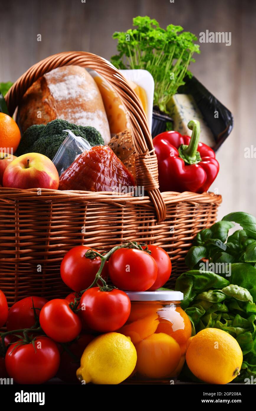 Wicker basket with assorted grocery products including fresh vegetables ...