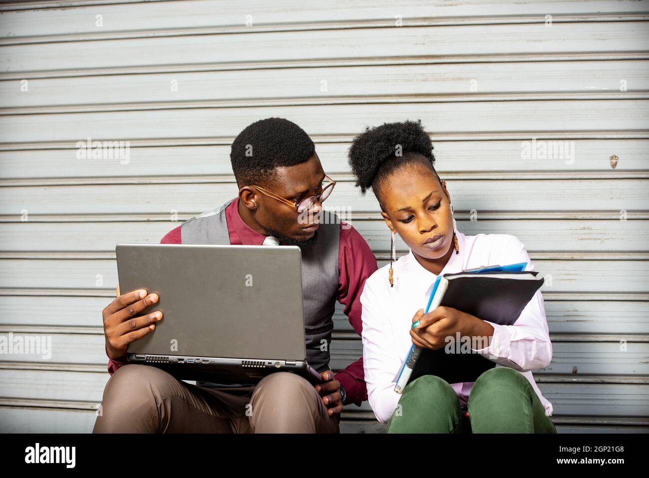 two young african discussing future project in an outdoor cafe carrying ...