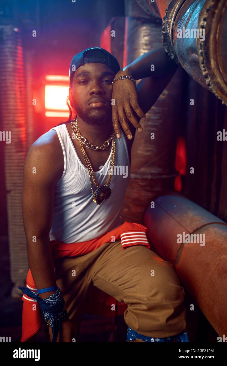 Stylish rapper in yellow hoodie and baseball cap poses in studio with ...