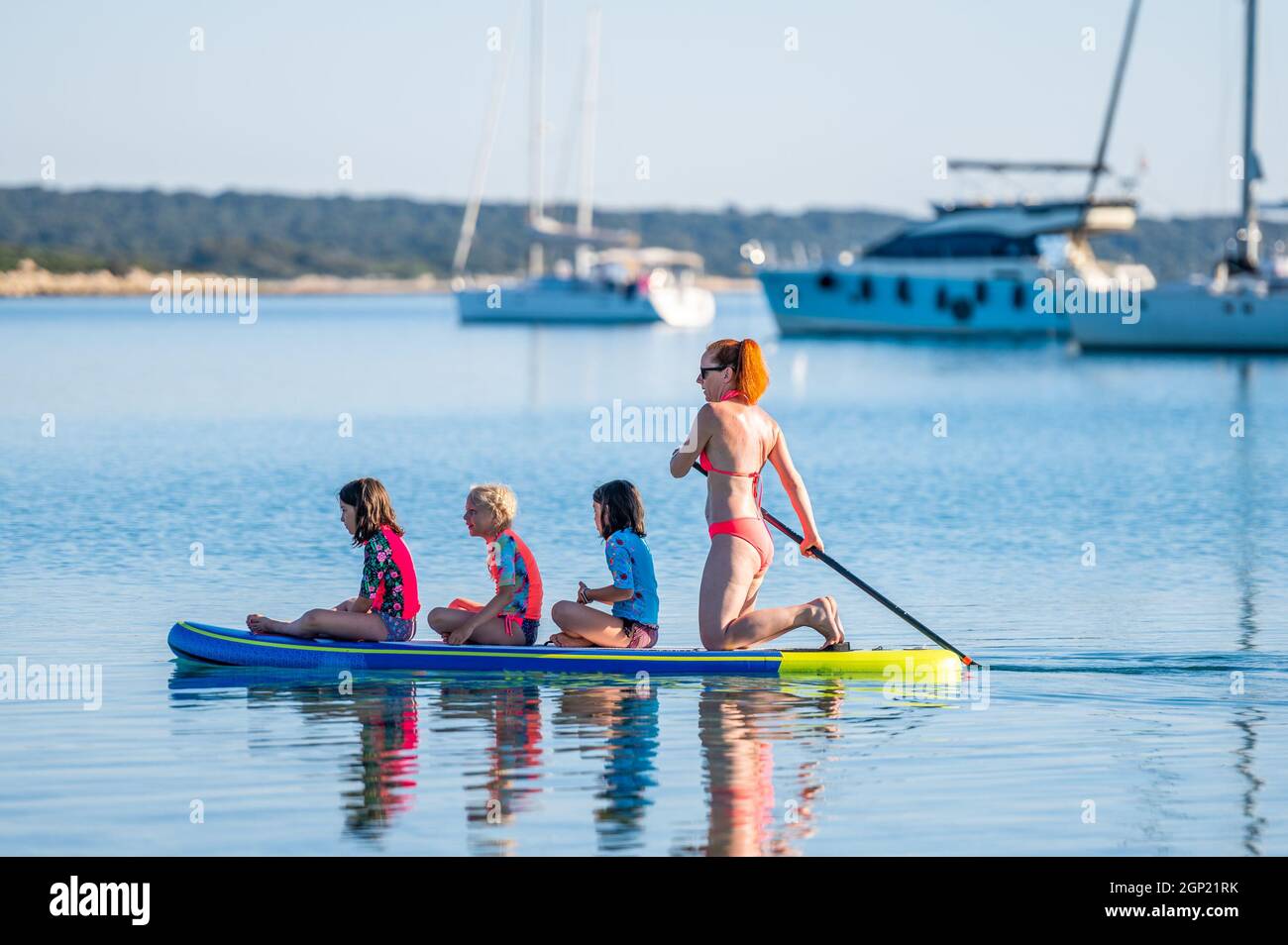 Happy Family on SUP stand up paddle on vacation. Active family riding ...