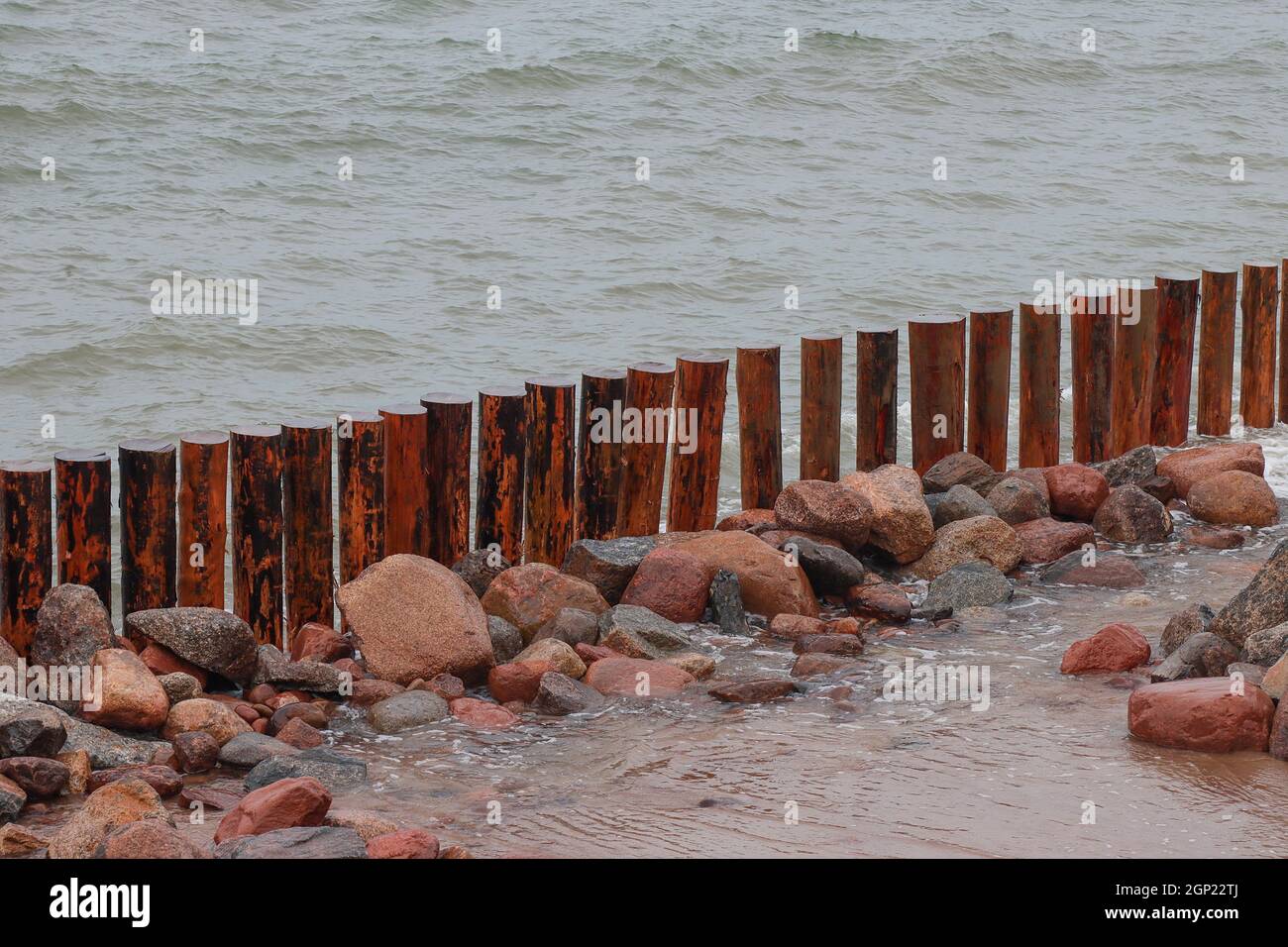 Fencing, breakwater from logs and stones at sea Stock Photo - Alamy