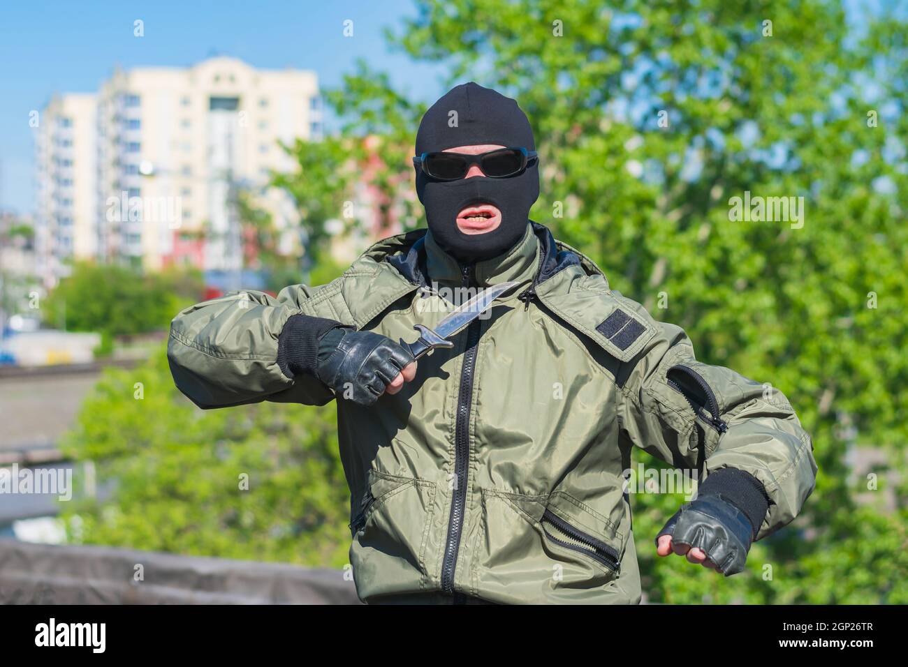 Street robber with a knife and a mask threatens and attacks people ...
