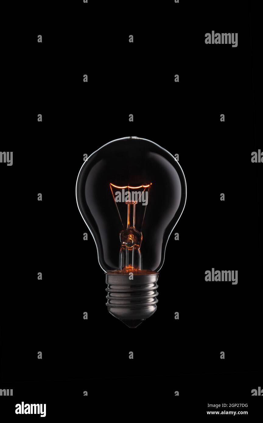 Burning Light bulb on black background Stock Photo - Alamy