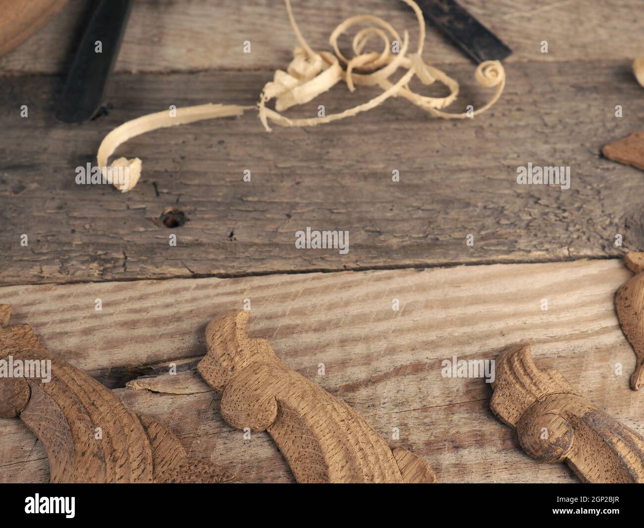 Carved oak decorative elements on a rustic workbench with chisels, text ...