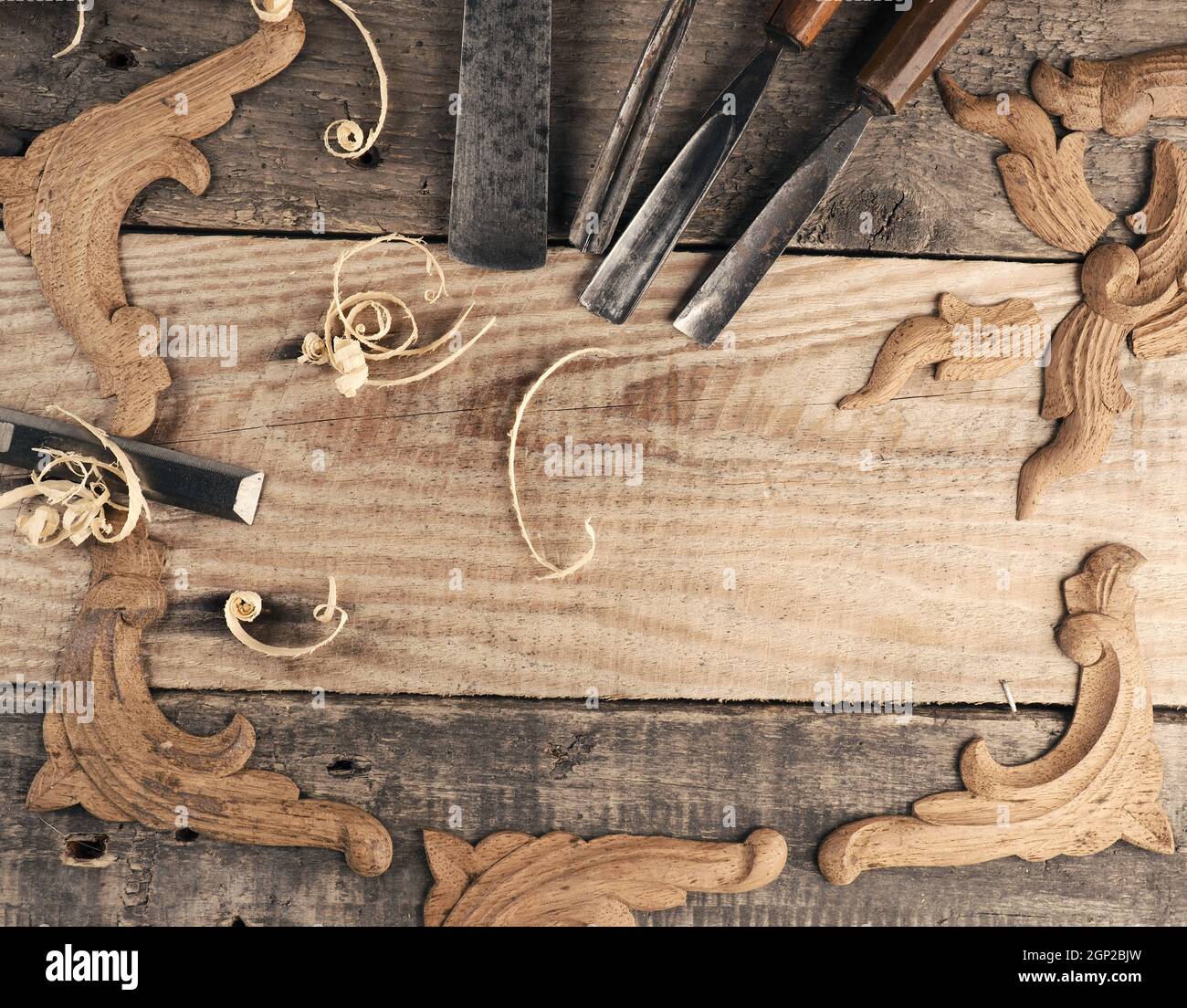 Carved oak decorative elements on a rustic workbench with chisels, wood ...