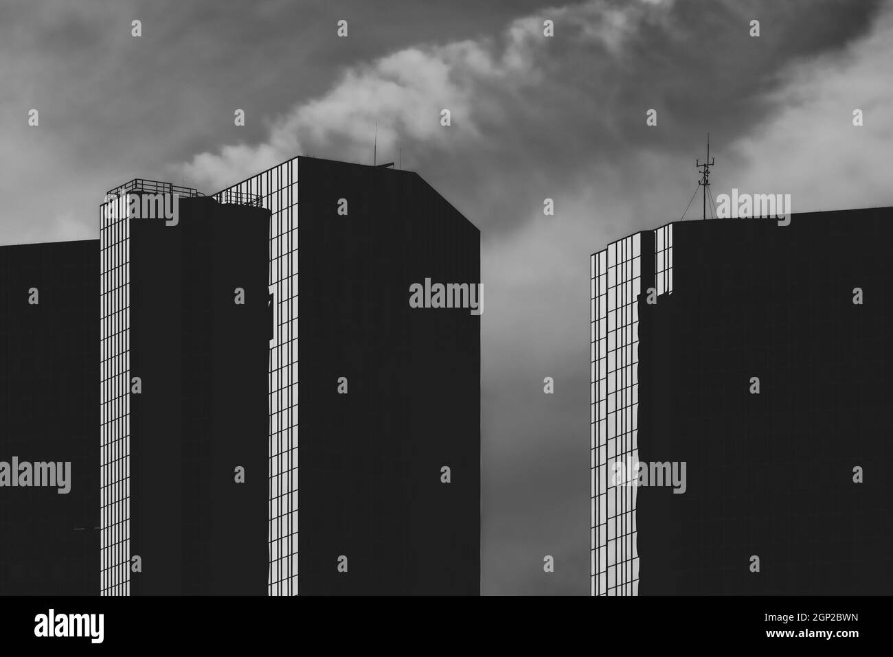 Grayscale shot of tall modern buildings with shadows covering them in ...