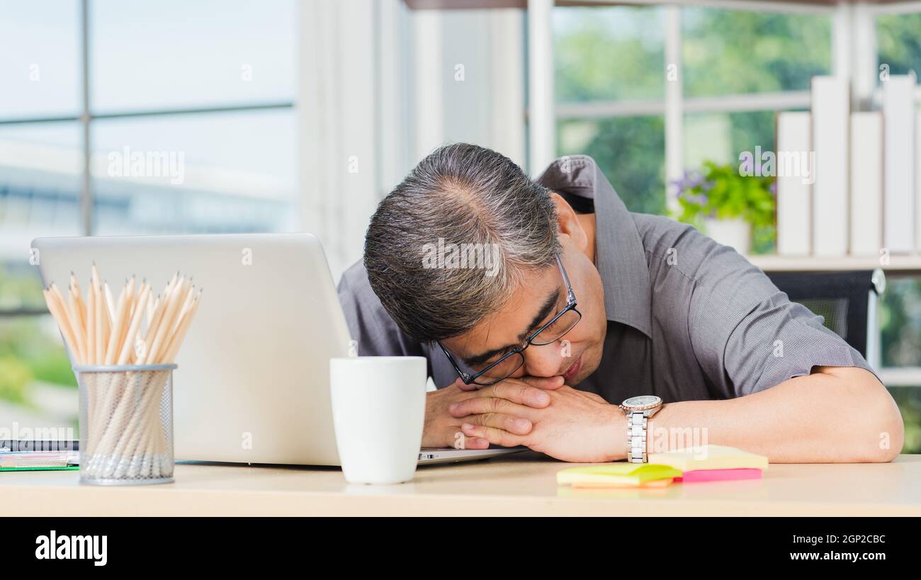 Asian businessman tired overworked he sleeping over a laptop computer ...