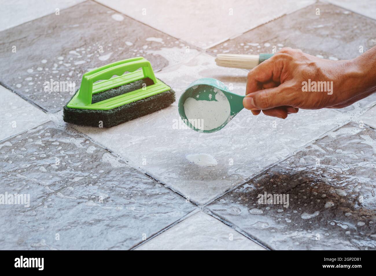 Close up a human hand pouring the detergent on the wet tile floor to ...