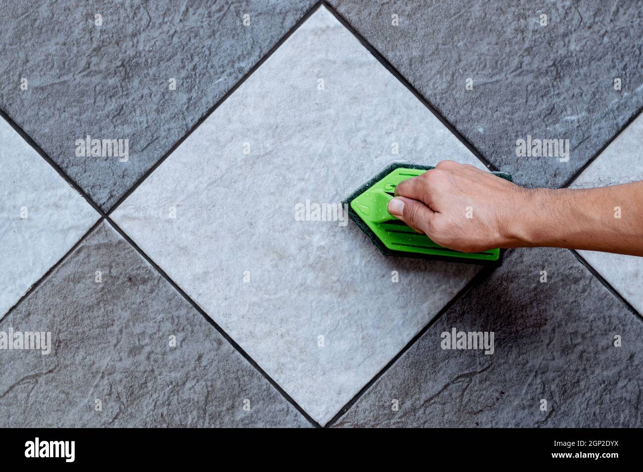 Top view of a human hand are using a green color plastic floor scrubber ...