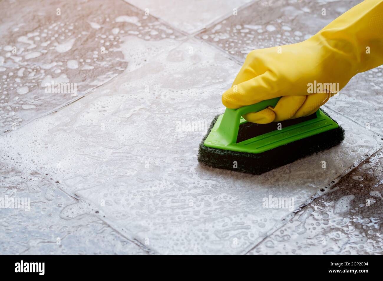 Human hands wearing yellow rubber gloves are using a green color ...